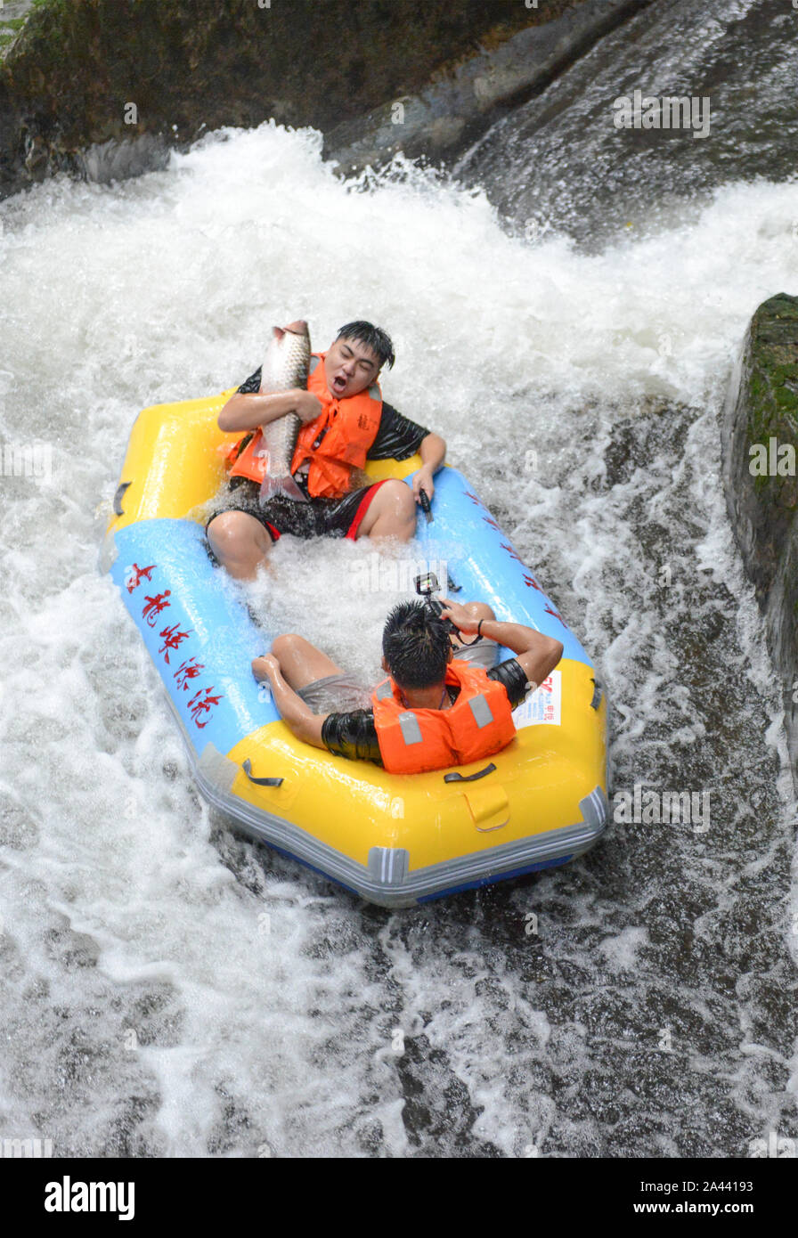 A crowd of tourists sitting on inflatable rafts jam a stream and catch ...
