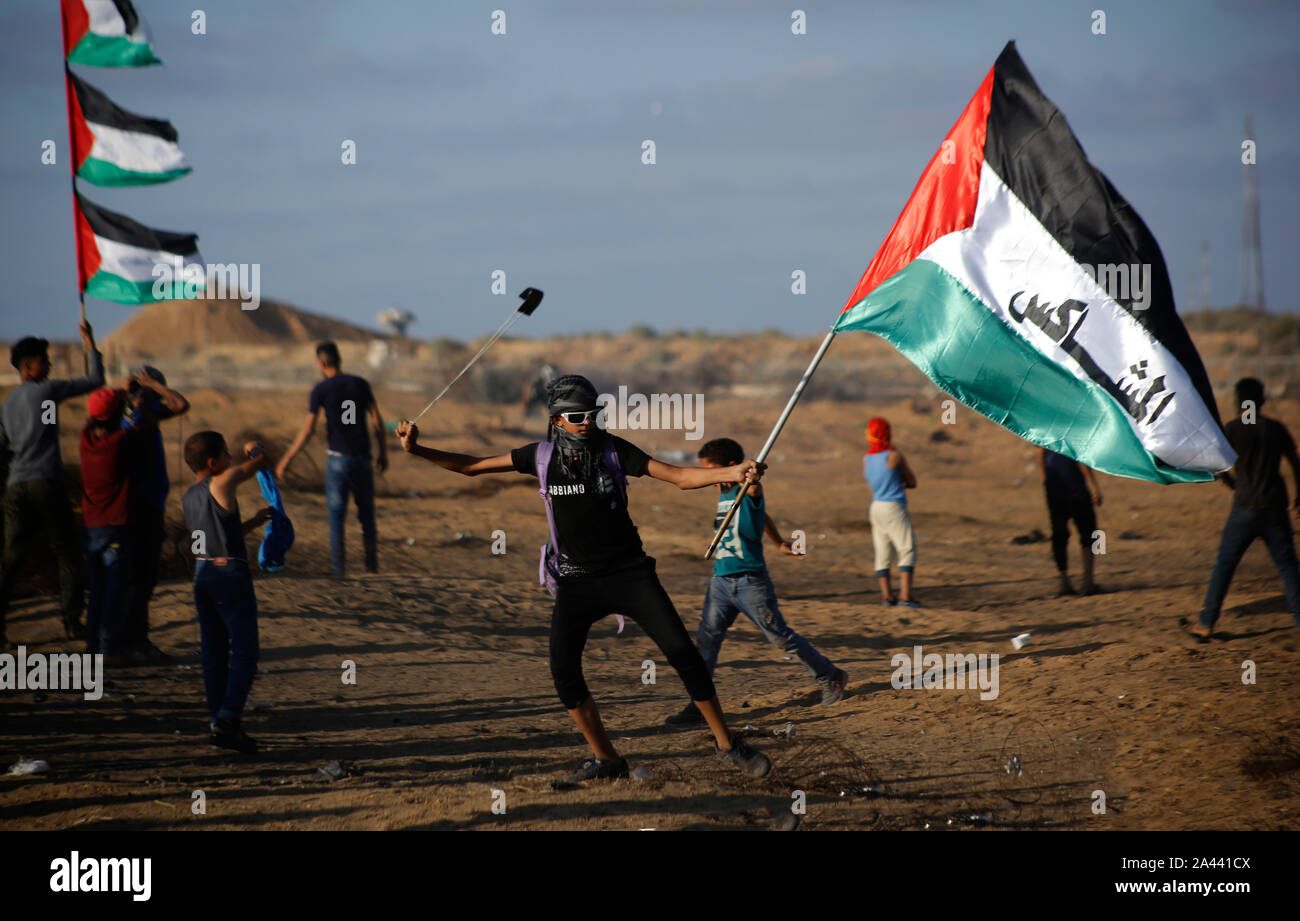 A Palestinian demonstrator uses a slingshot to throw stones during an ...