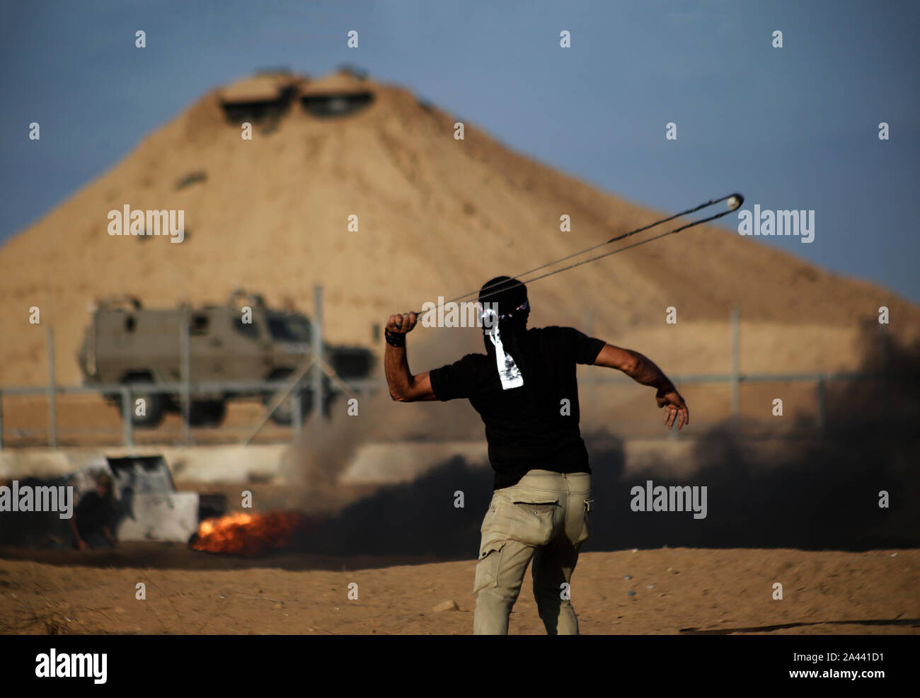 A Palestinian demonstrator uses a slingshot to throw stones during an ...