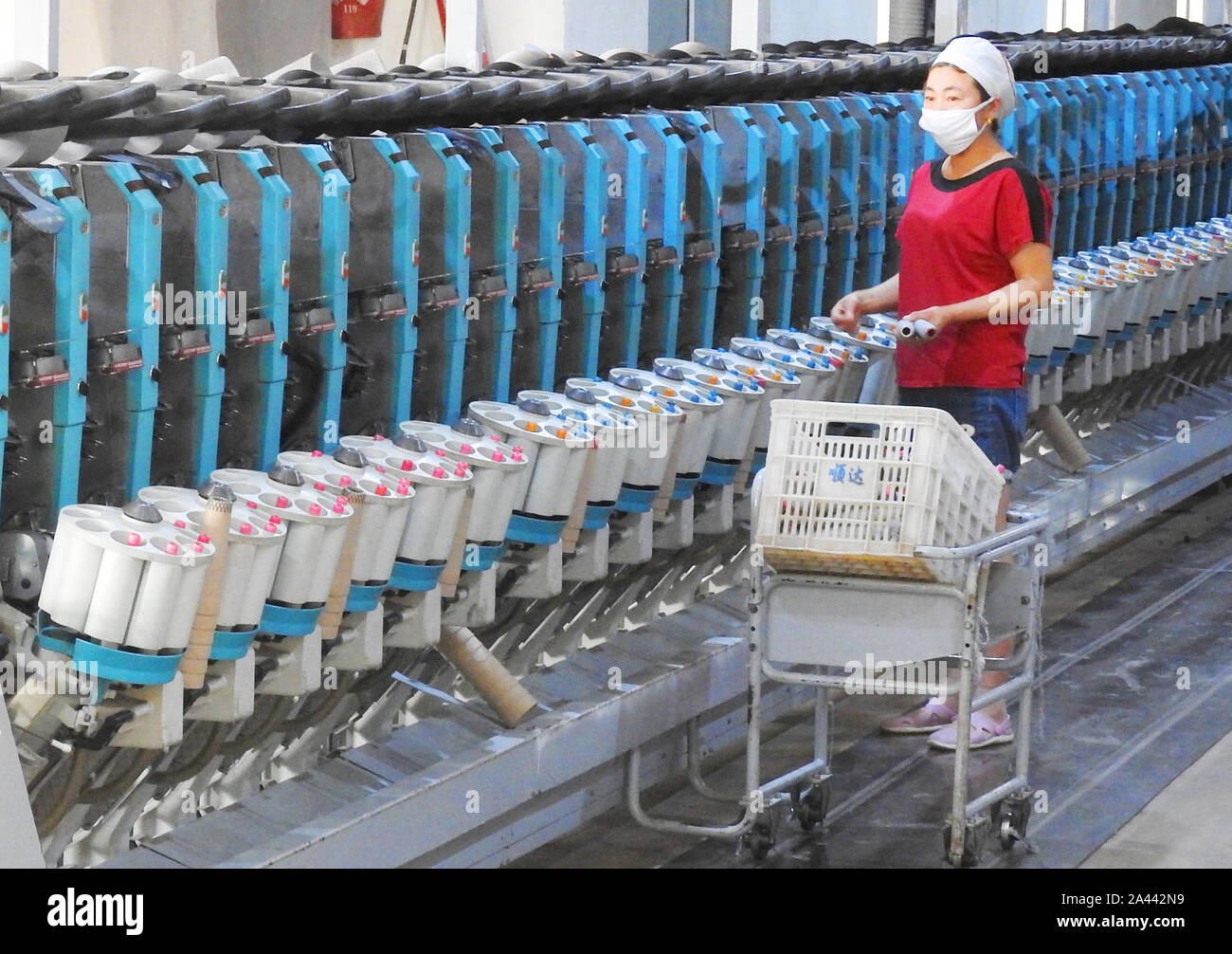 A female Chinese worker handles production of yarn at a textile factory in Lianyungang city ...