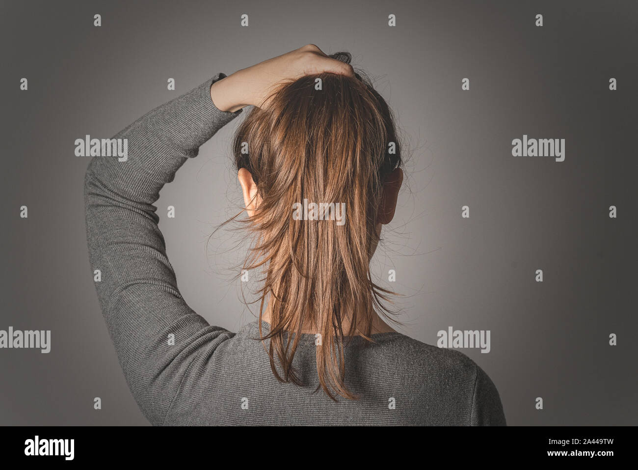 Woman holding bunch of hair in her hand isolated on gray background ...