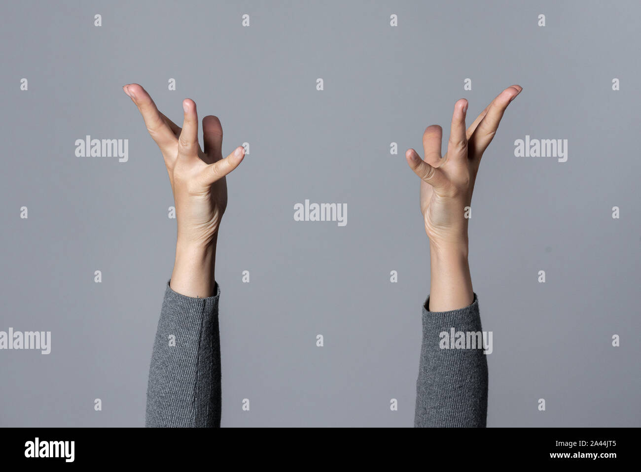 Woman standing with her hand raised up isolated on gray background ...