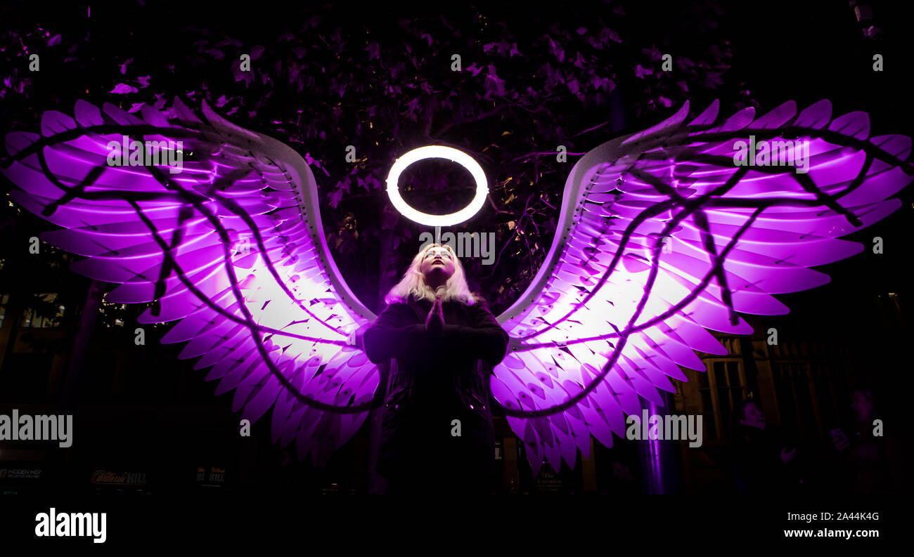 A woman stands in front of an art installation titled Angels of Freedom ...