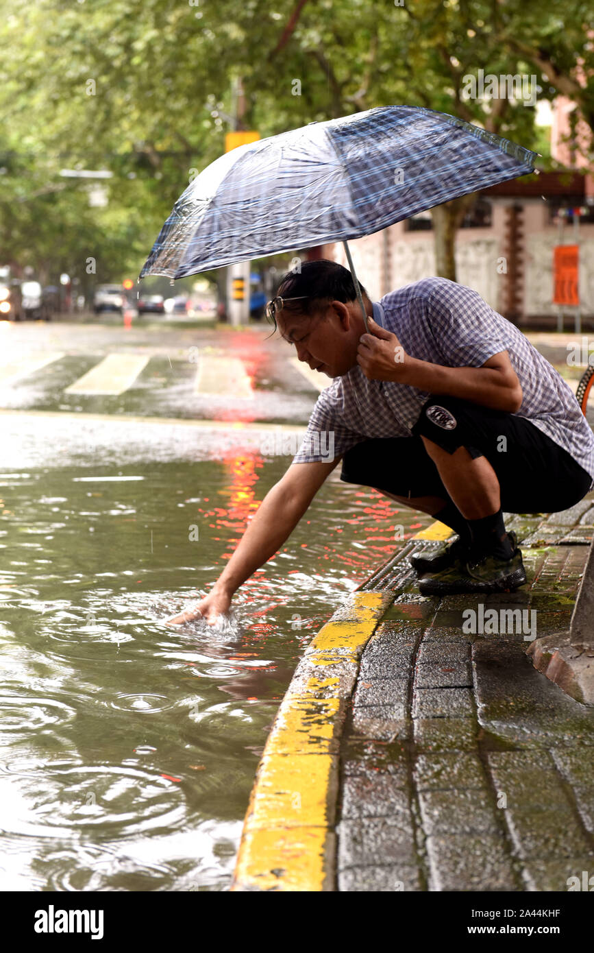 A local resident clear away stones and leaves on a flooded road in ...