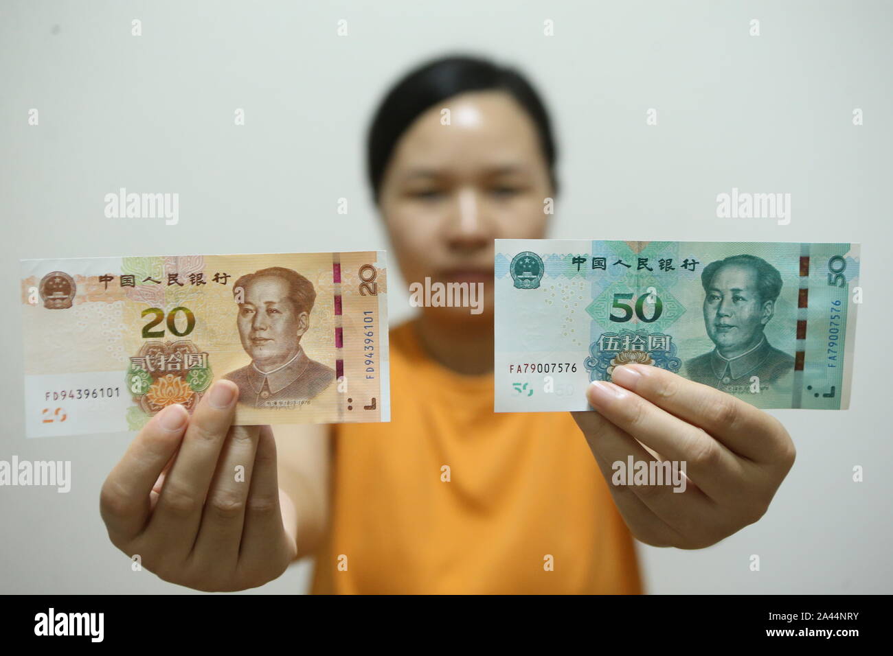 A person shows the 20-yuan, left, and 50-yuan renminbi bill of the ...