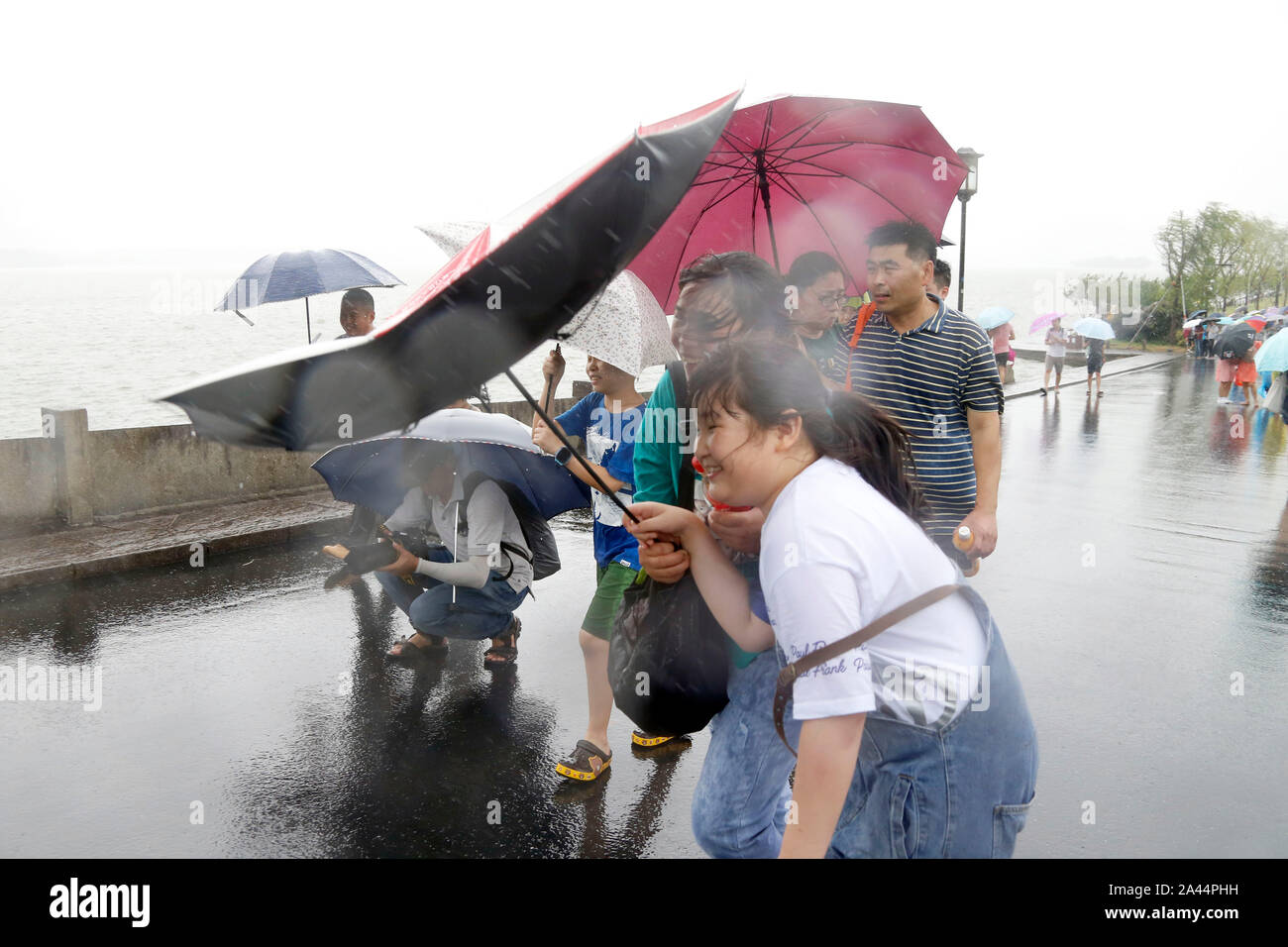 Tourists struggle with their umbrellas in heavy rain and strong wind ...