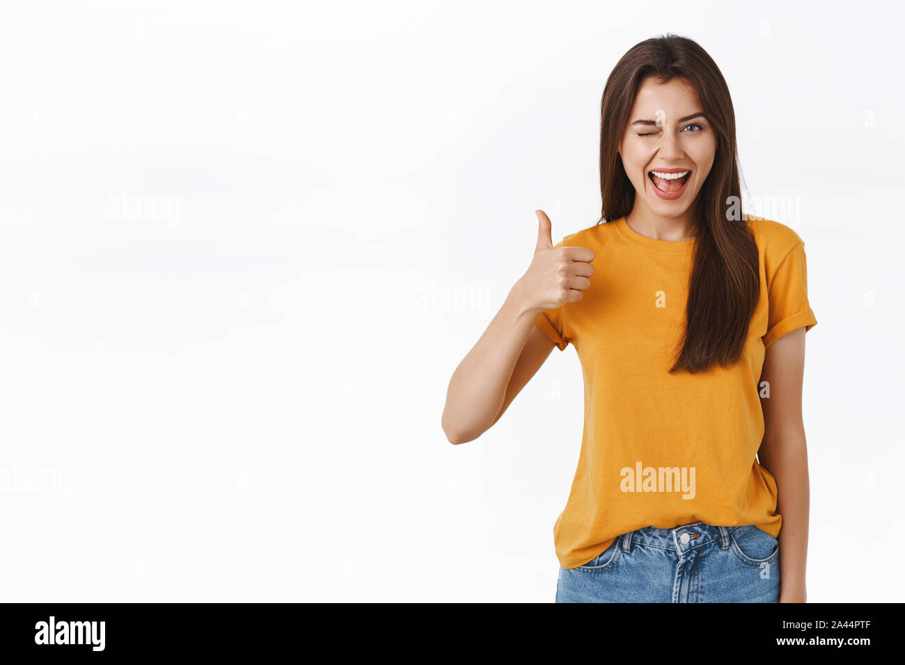 Cheeky and carefree, funny cute brunette girl showing thumbs-up wink ...