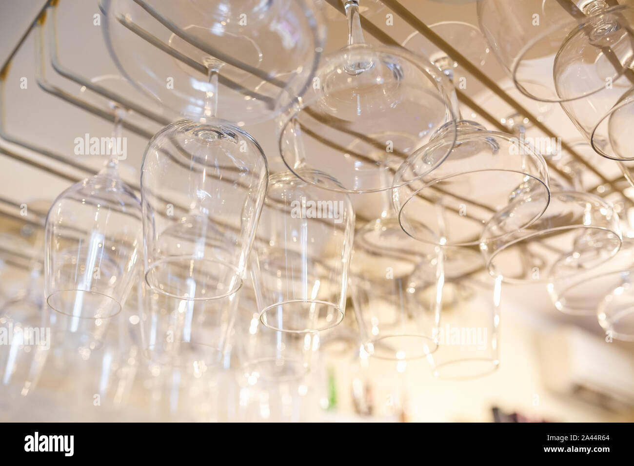 rows of empty glasses hang on reception party table in bar. Close up at ...