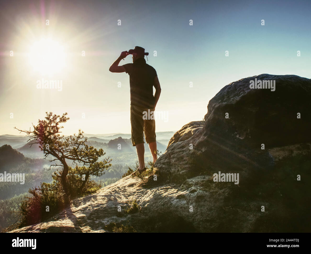 The man standing high on cliff. Hiker climbed up to rocky peak and ...