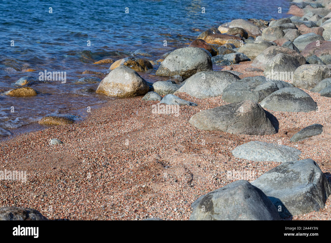 Stones and sand in clear water on the beach of a mountain lake Issyl ...