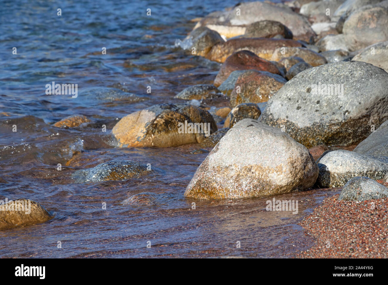Stones and sand in clear water on the beach of a mountain lake Issyl ...