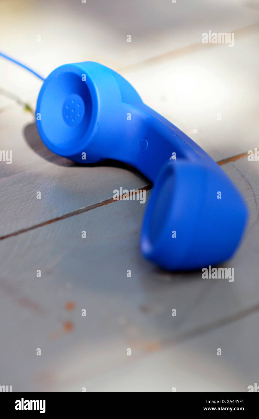 single blue plastic telephone handset on striped table Stock Photo - Alamy