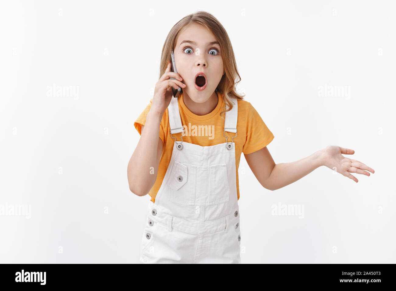 Impressed charismatic blond little girl, child talking on phone ...