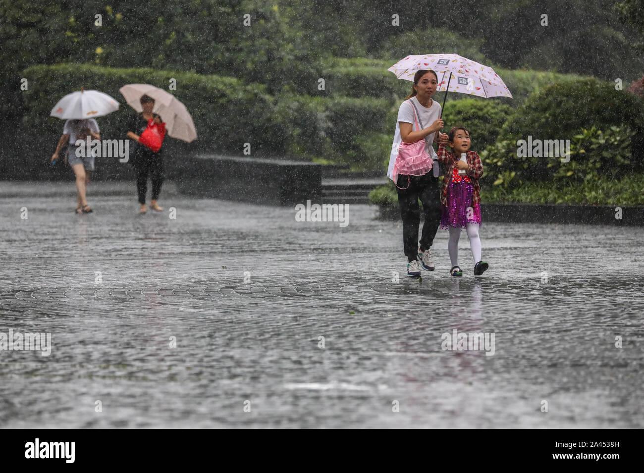 Local residents shield themselves with umbrellas in heavy rain and ...