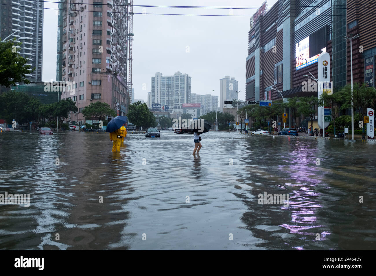 Pedestrians walk on a flooded road after a heavy rainstorm caused by ...