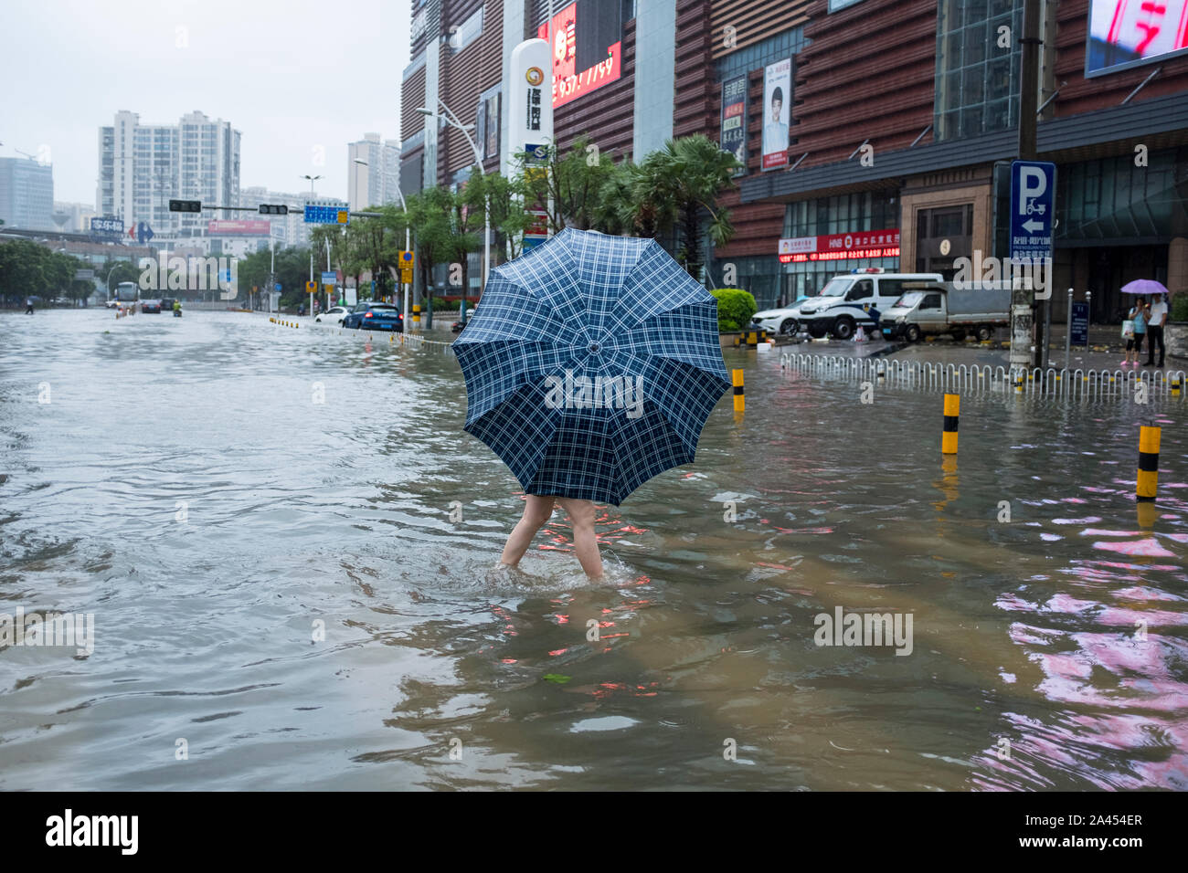 Pedestrians walk on a flooded road after a heavy rainstorm caused by ...