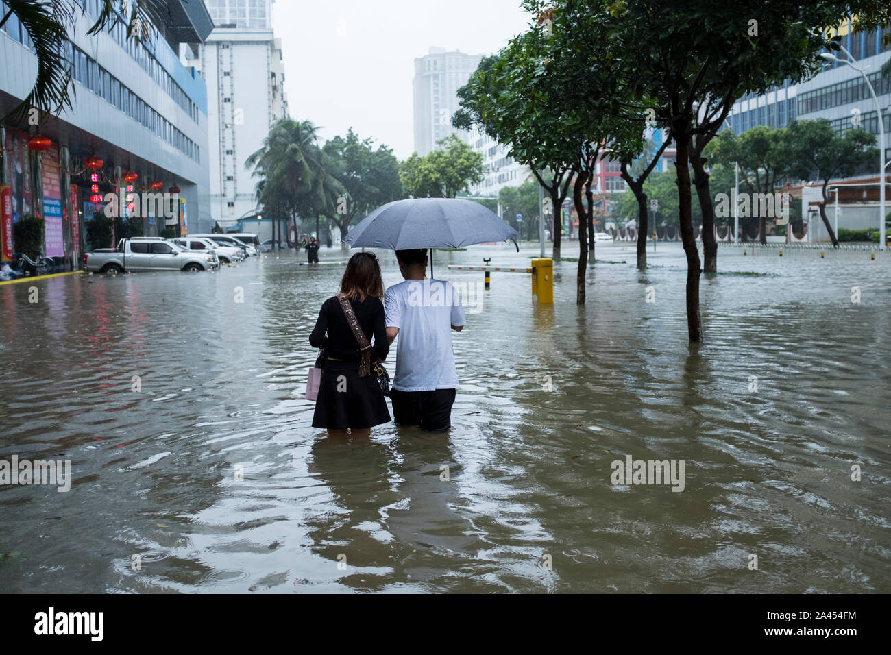 Pedestrians walk on a flooded road after a heavy rainstorm caused by ...