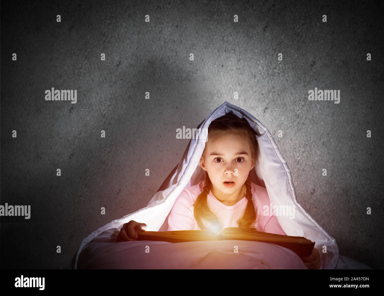 Scared little girl reading book in bed Stock Photo - Alamy