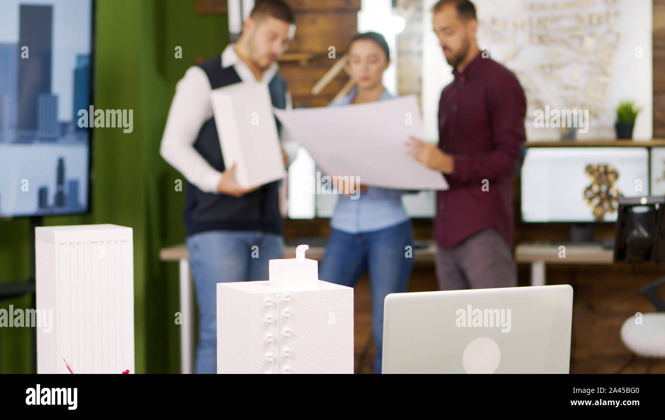 Slide view of building models with architects working in the background ...