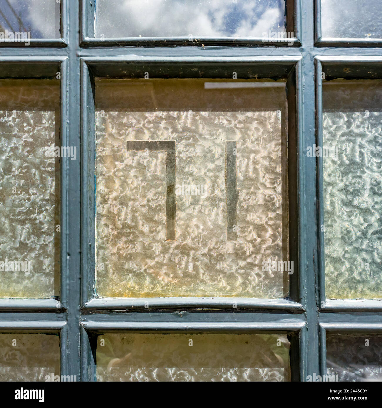 House number seventy one (71) cut out of adhesive film stuck to window ...