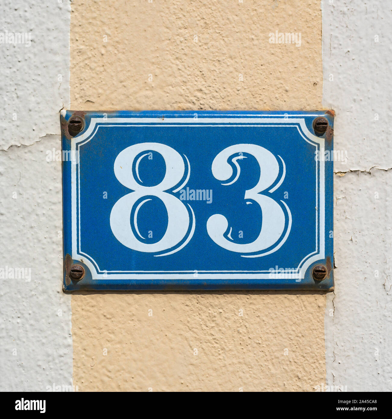 enameled house number eighty three on a wall with a peach colored ...