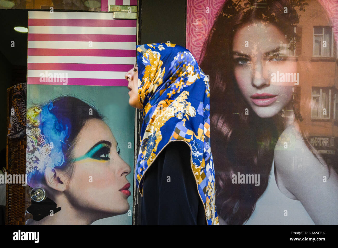 Veiled Muslim woman walking between posters of models, Istanbul, Turkey ...