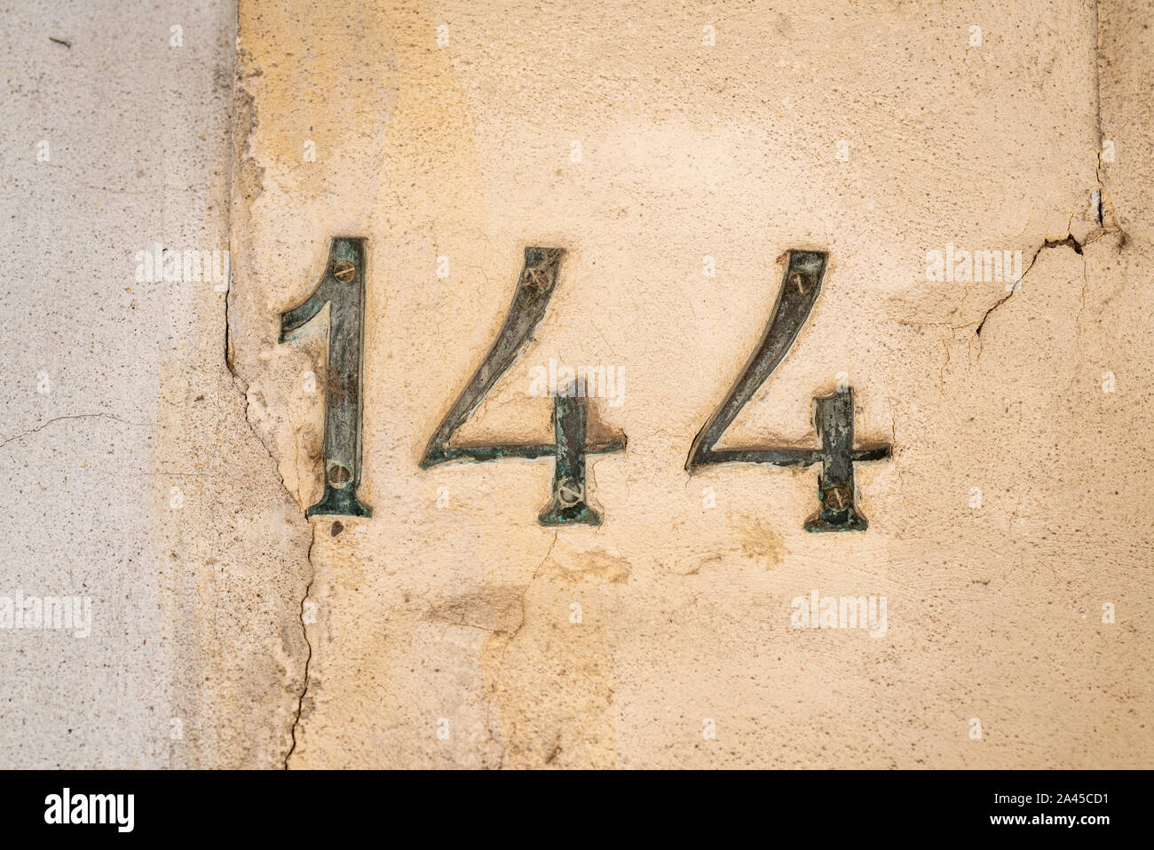 Bronze house number one hundred and forty four on a crackled wall Stock ...