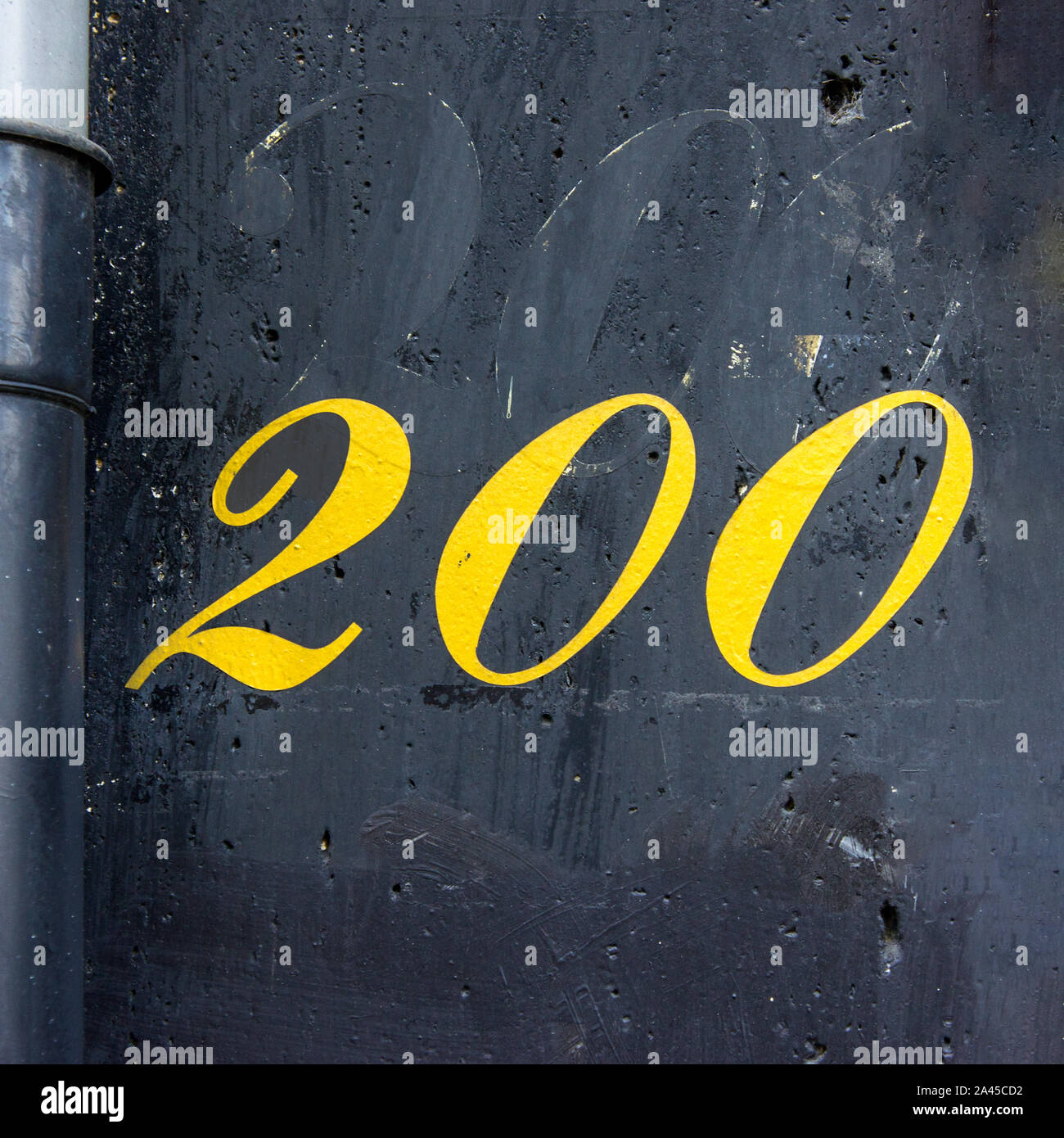 Yellow house number two hundred (200) Hand painted on a black wall ...