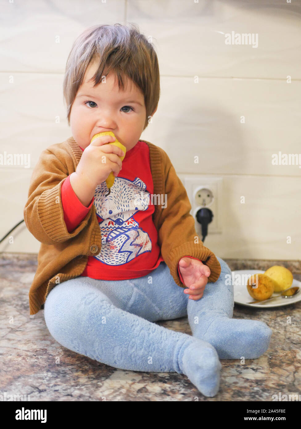 little child eats a pear. child boy eating fruits at a high stoic. in ...