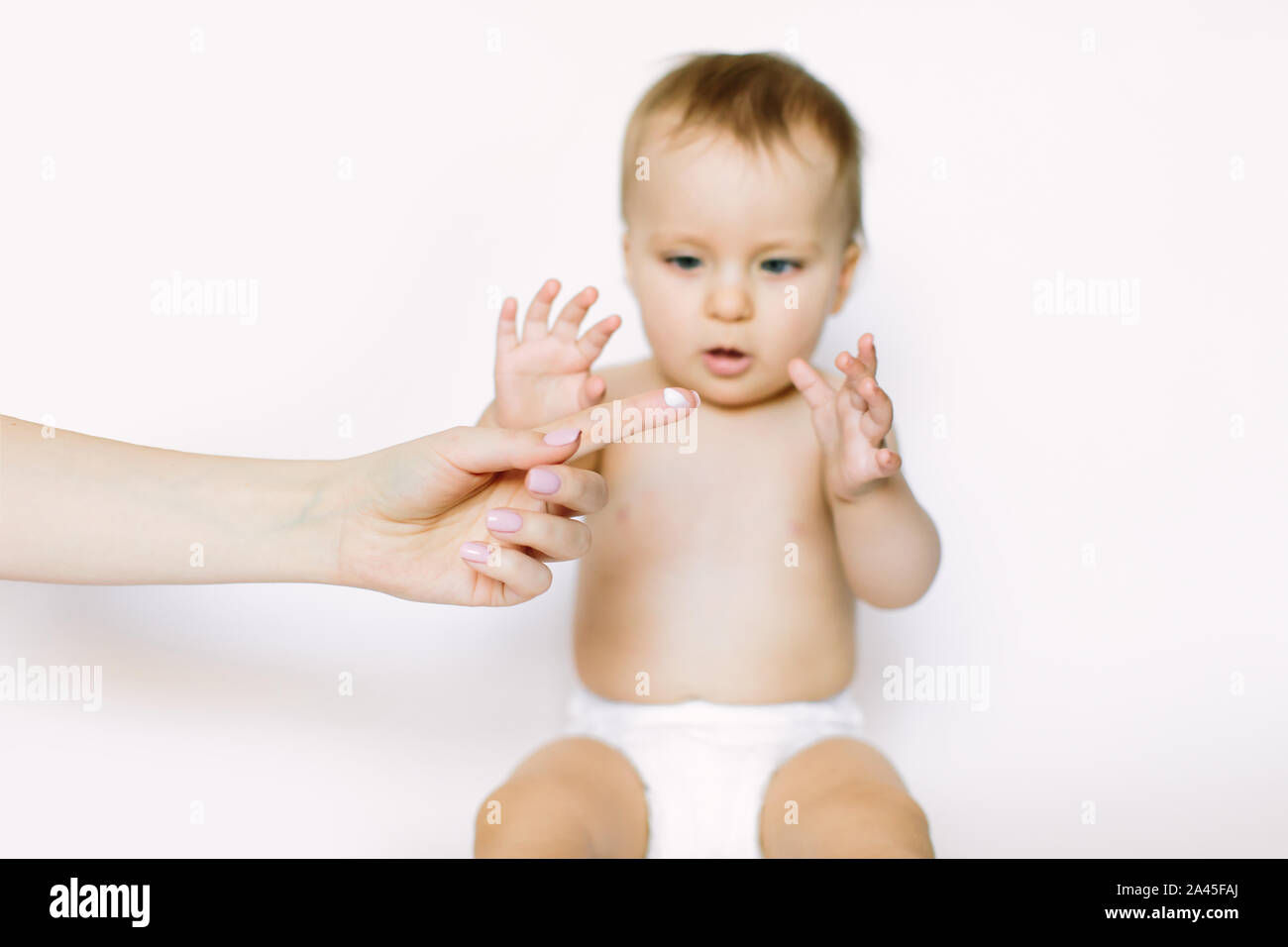 Young mother applying face kids cream on her baby girl face against ...