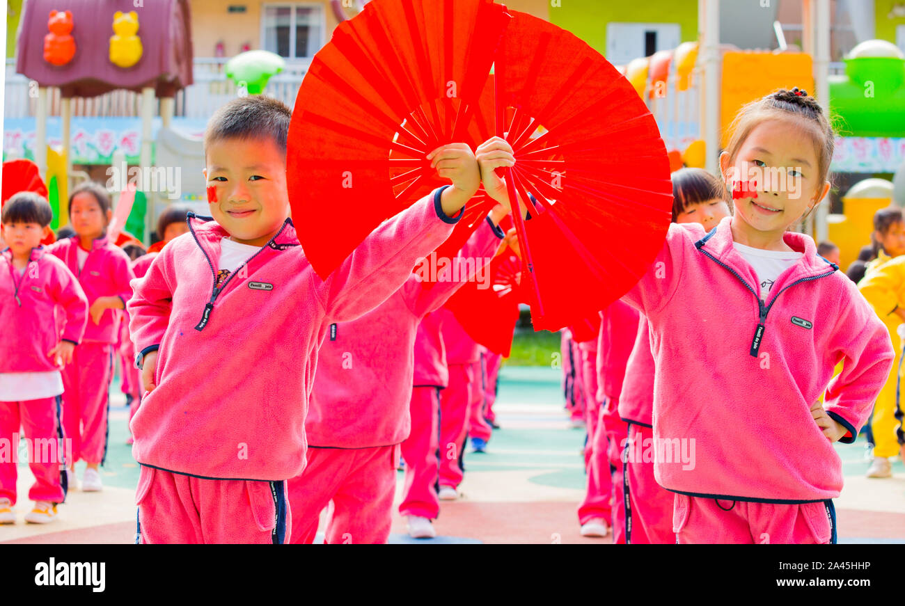 Kindergarten kids do group red fan dance to embrace the upcoming of the ...
