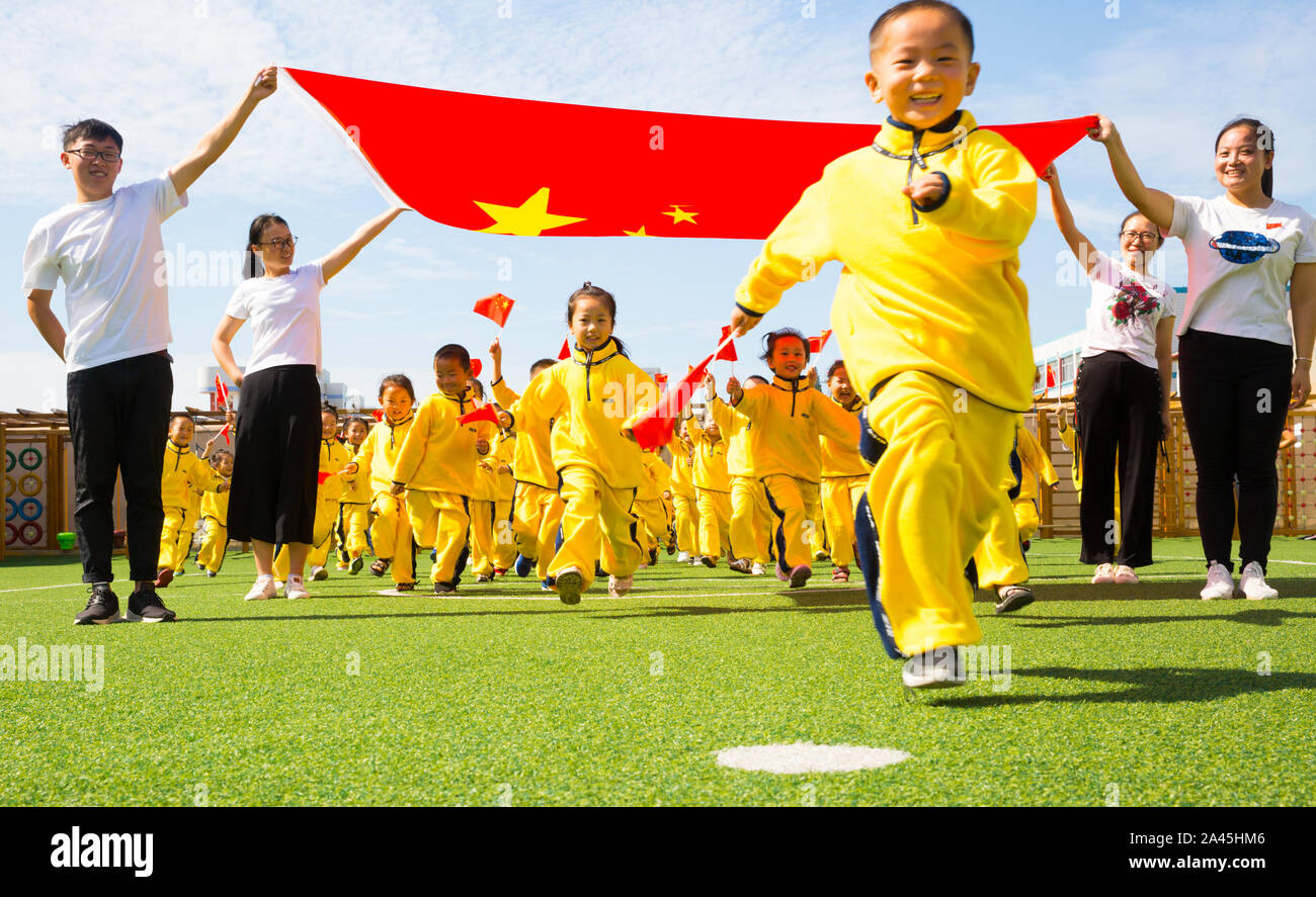 Kindergarten kids pass under a giant Chinese flag to embrace the ...