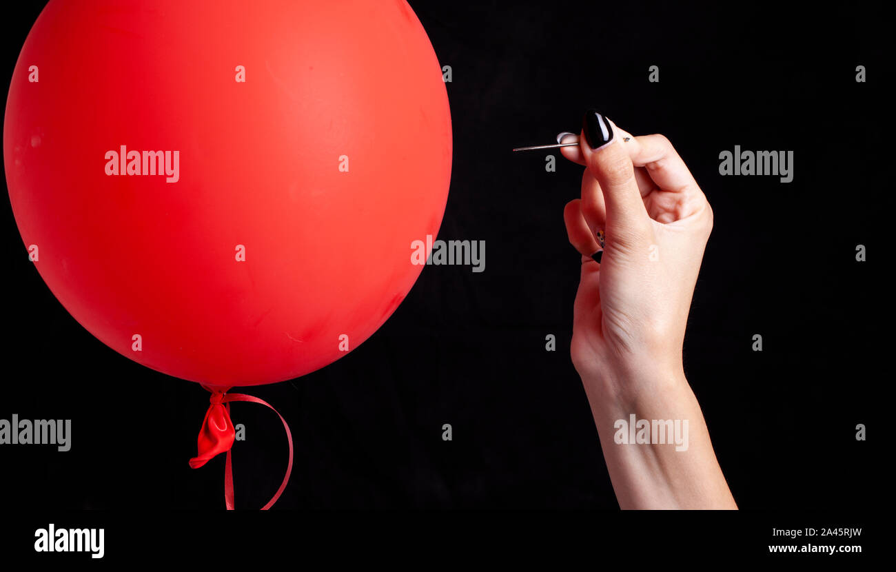 burst red balloon with a needle - danger concept Stock Photo - Alamy