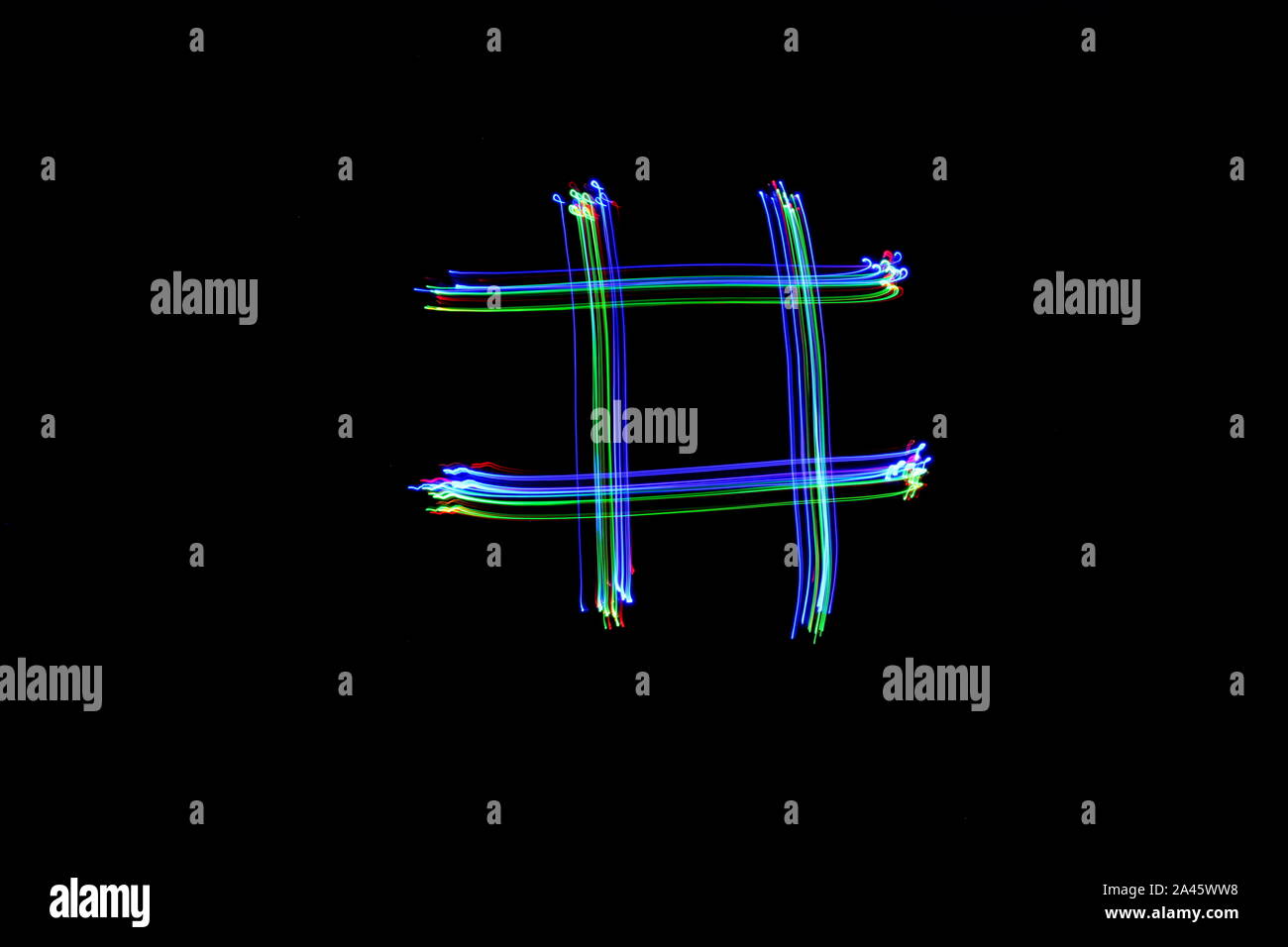 Long exposure photograph of a hashtag shape symbol in neon colour in a ...