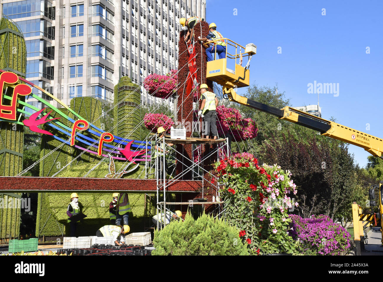 Workers work on a tree mosaiculture on the Changan Boulevard in Beijing ...