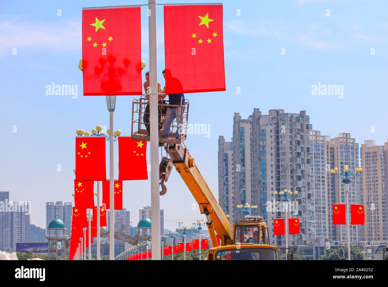 Workers hang national flags in streets to celebrate the 70th National ...