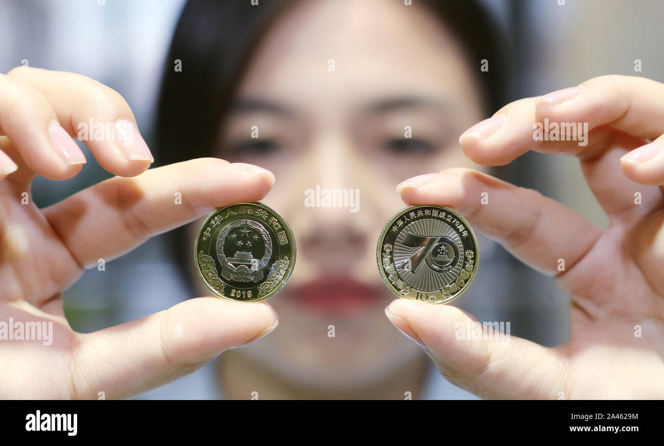 A bank staff demonstrates two sides of the 10 Yuan commemorative coin ...