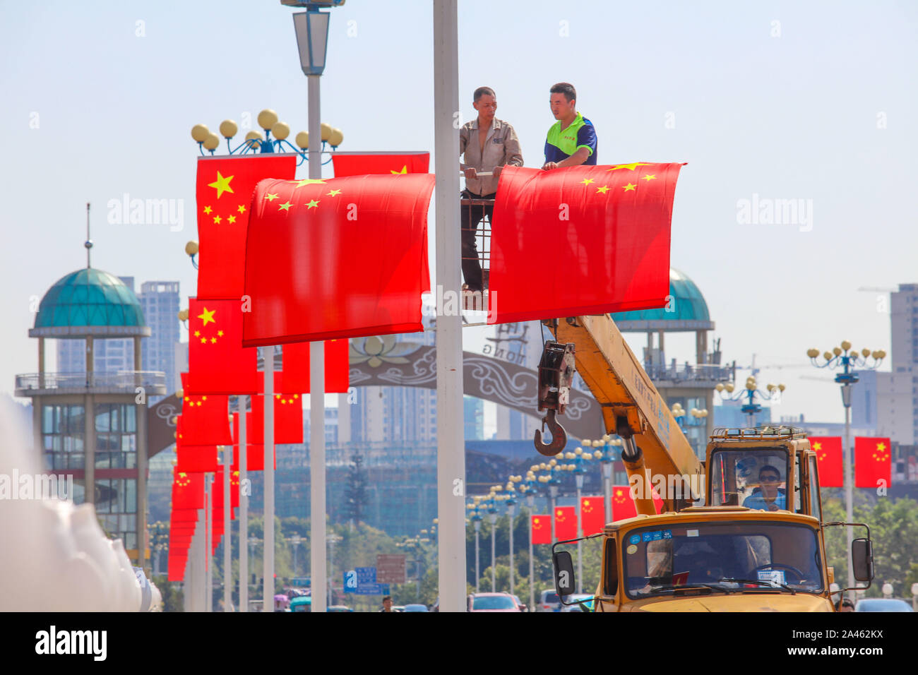 Workers hang national flags in streets to celebrate the 70th National ...