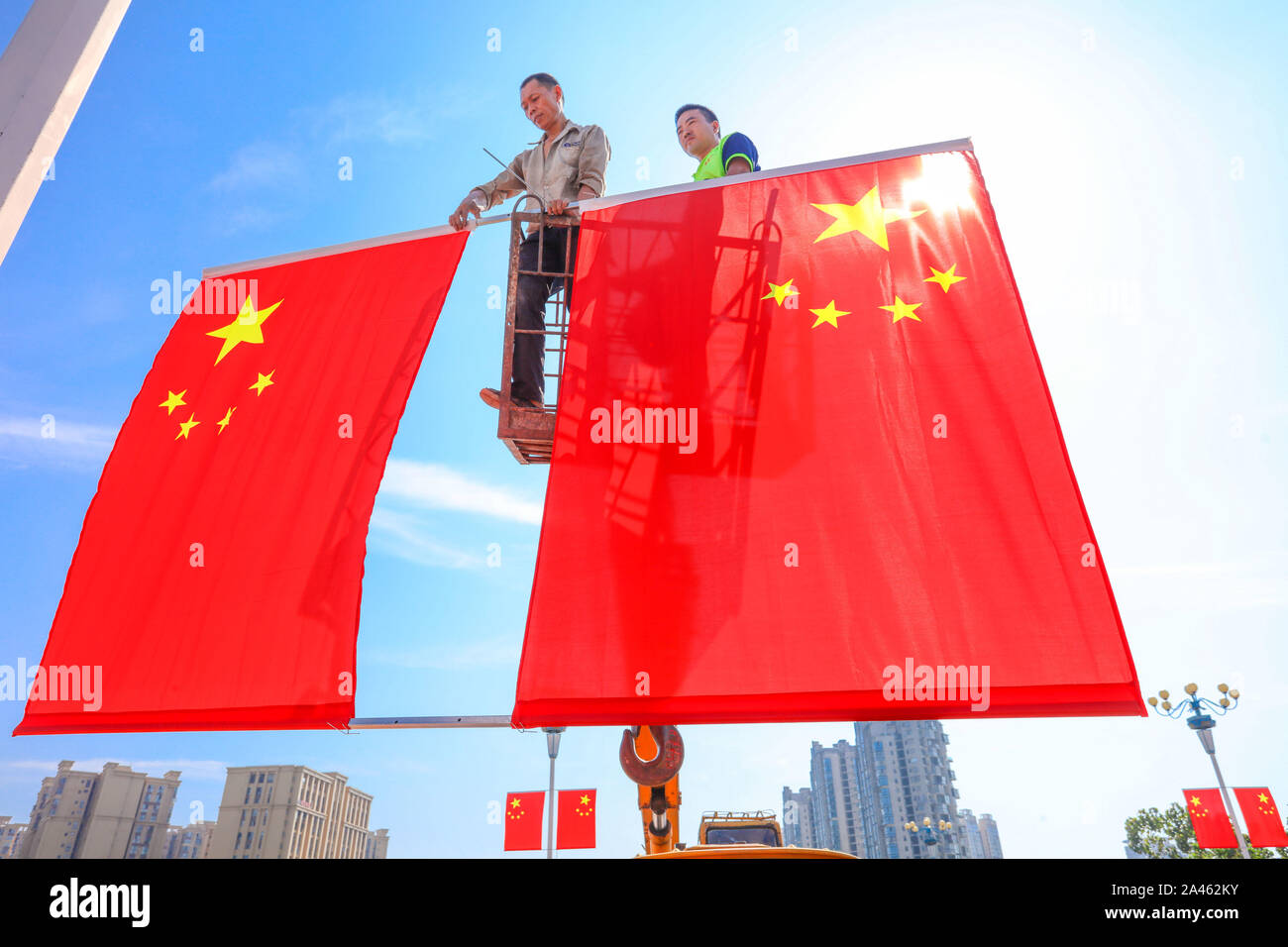 Workers hang national flags in streets to celebrate the 70th National ...