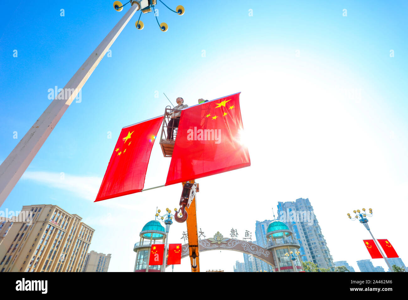 Workers hang national flags in streets to celebrate the 70th National ...