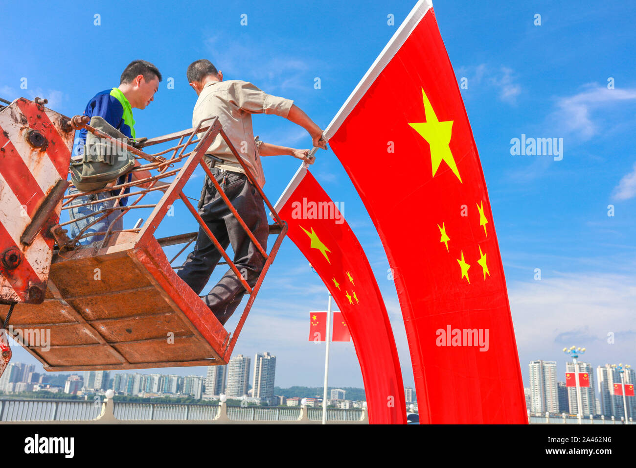 Workers hang national flags in streets to celebrate the 70th National ...