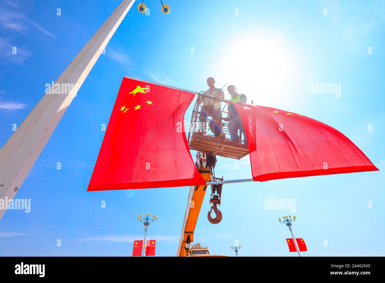 Workers hang national flags in streets to celebrate the 70th National ...
