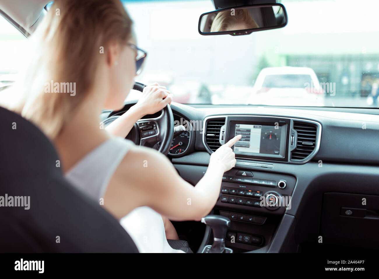 woman driving car, choosing navigation on monitor screen, presses touch ...