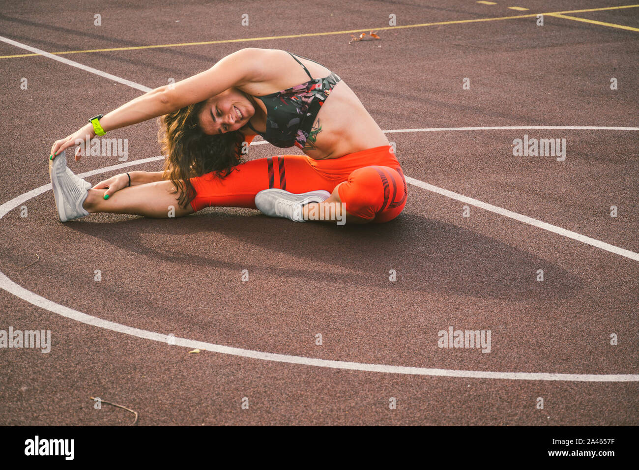 Woman Athlete Stretching Legs On Stadium. Female Runner Stretching ...