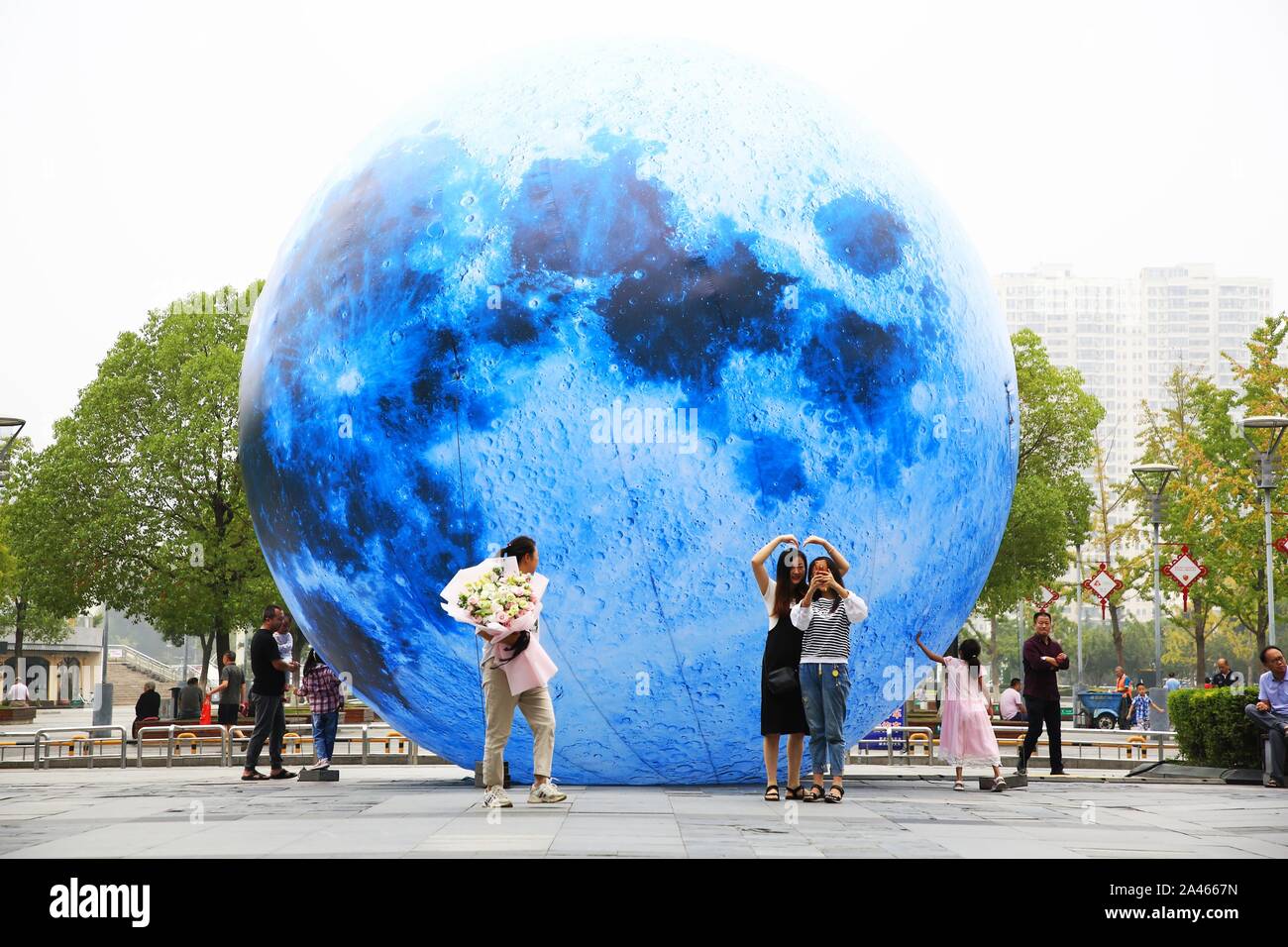 People take pictures of the man-made blue moon set up on the street to ...