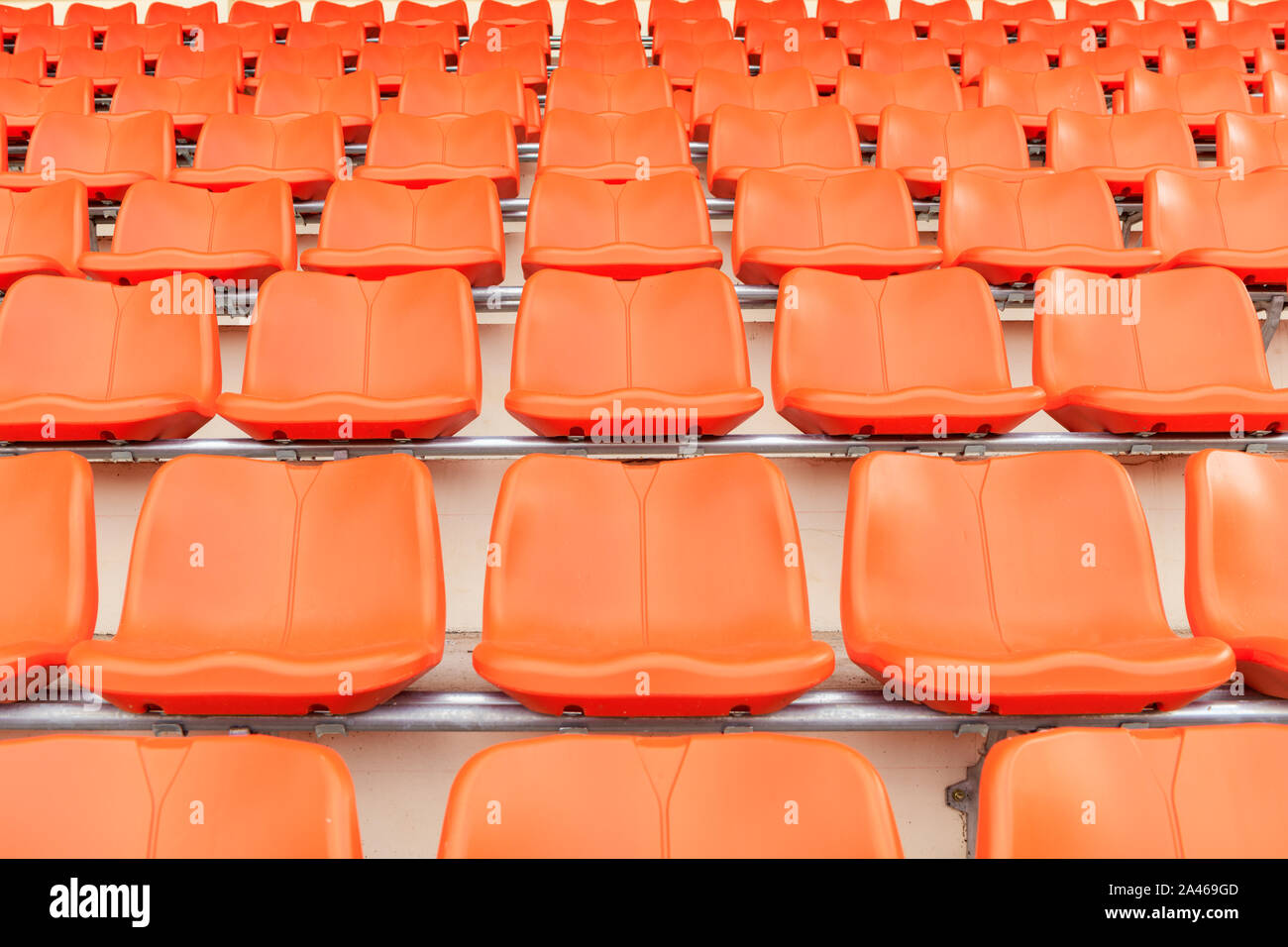 Rows of empty orange plastic grandstand seats at an indoor sport ...