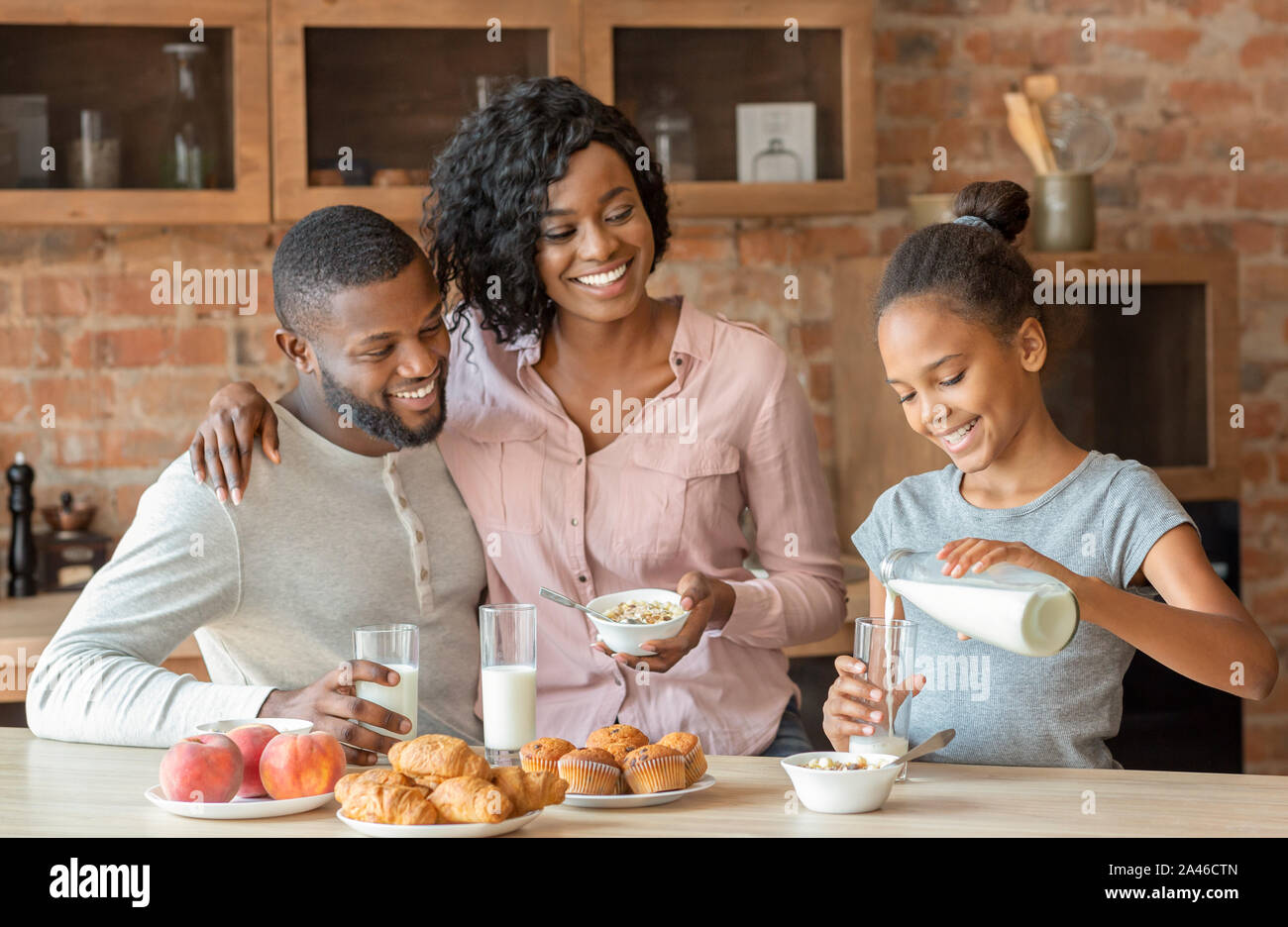 Beautiful family drinking milk, eating sweets together at kitchen Stock ...