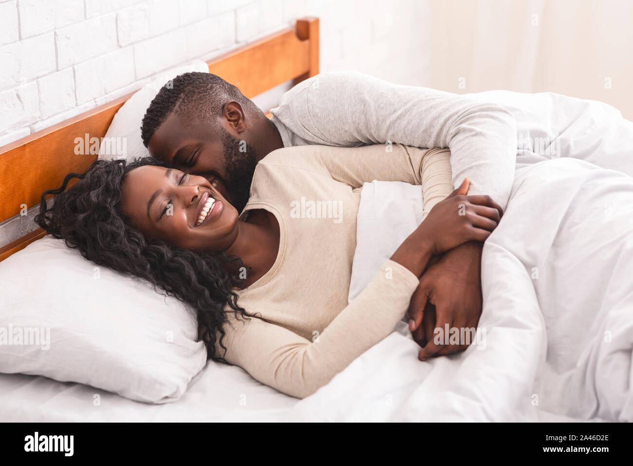 Young black couple waking up in bed in the morning Stock Photo - Alamy
