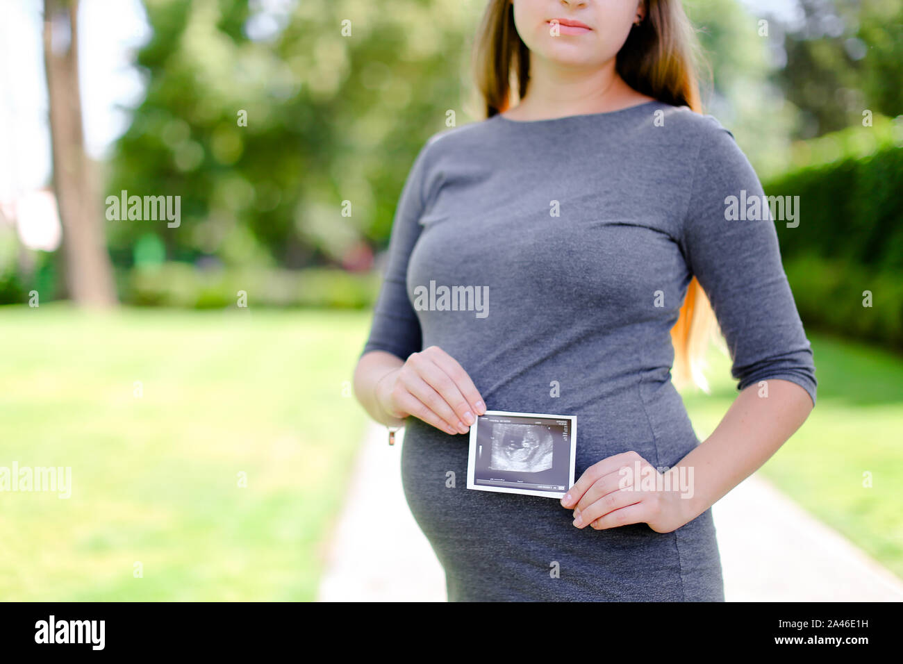 Young pregnant girl wearing grey dress keeping ultrasound photo ...