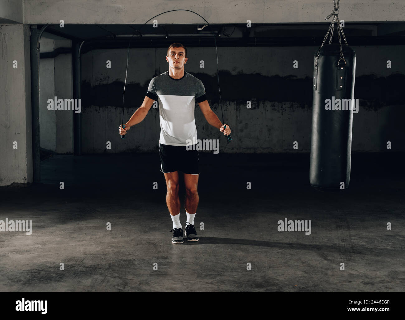 Masculine man skipping rope in dark. Portrait of muscular young man ...